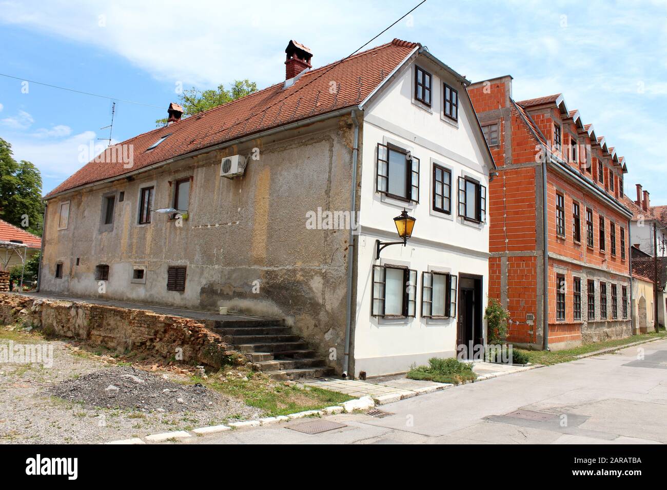 Narrow elongated old dilapidated suburban family house with cracked facade and renovated front ...