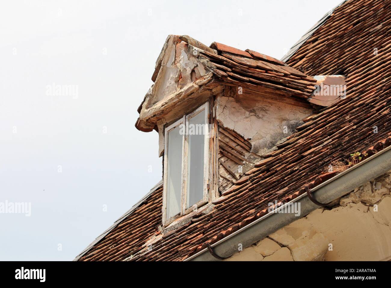 Old destroyed roof window with cracked wooden frame on top of ruins of abandoned suburban family ...