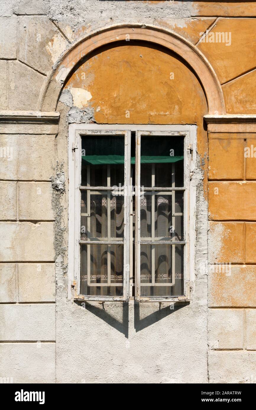 Open dilapidated window with white wooden frame secured with strong ...