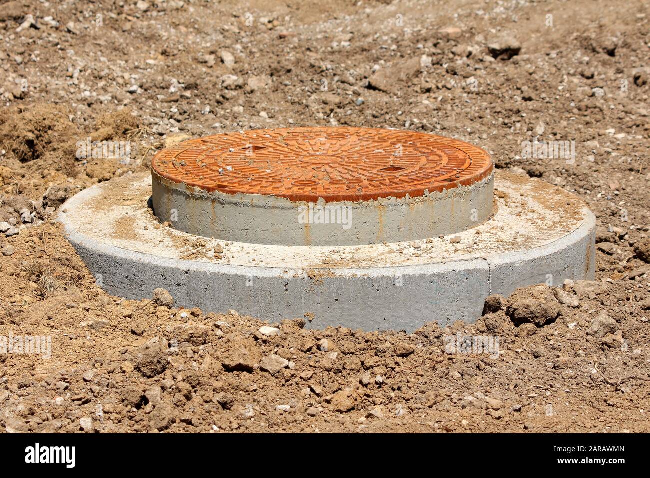 Rusted heavy metal round manhole cover surrounded with concrete ...