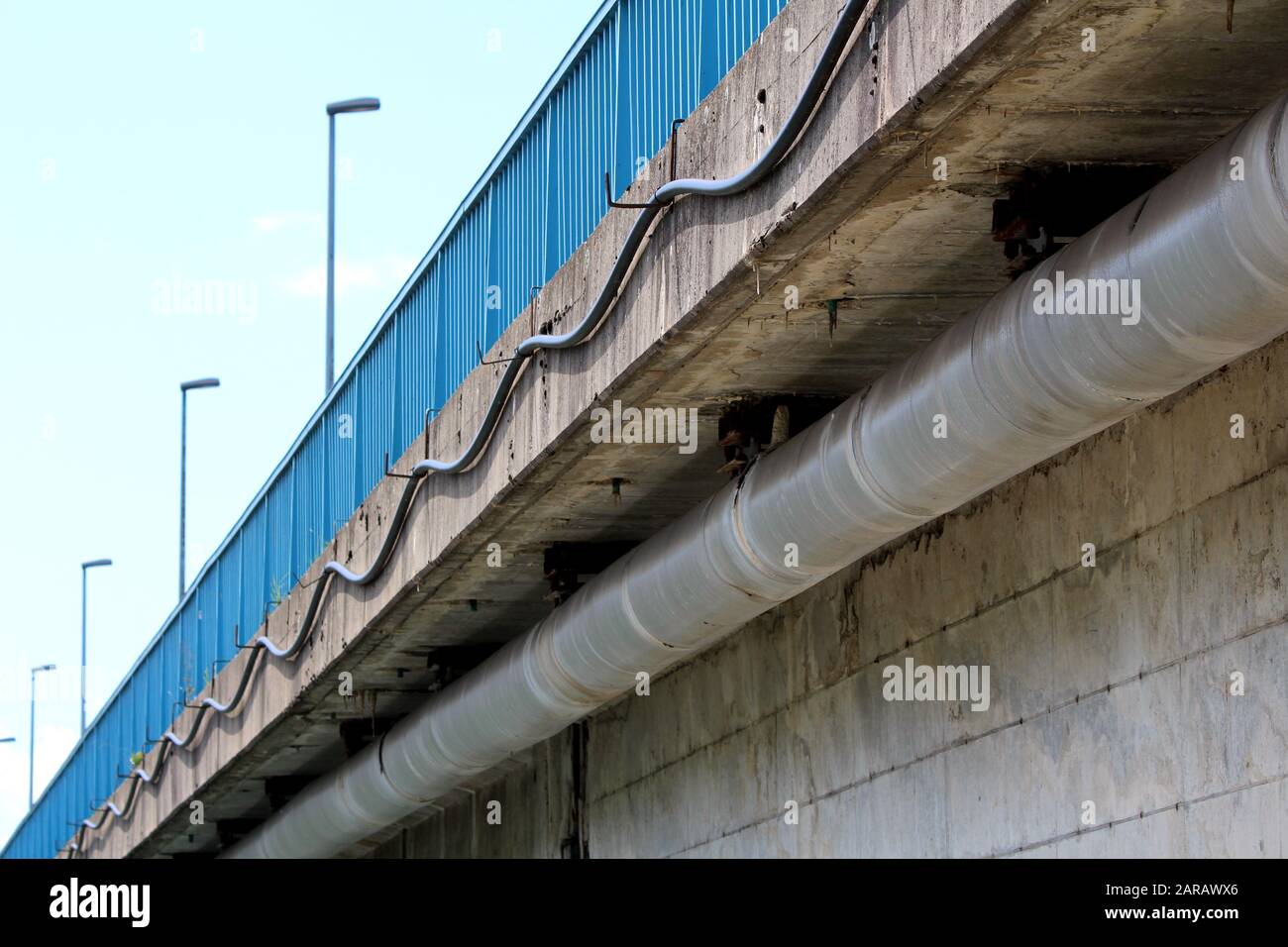 Side view of old partially renovated bridge with new blue metal fence ...
