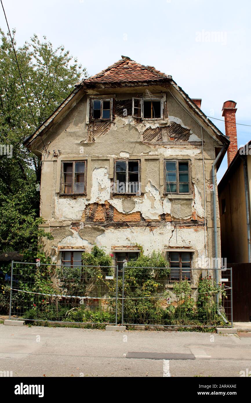 Tall narrow old abandoned suburban family house ruin with broken windows and cracked dilapidated ...