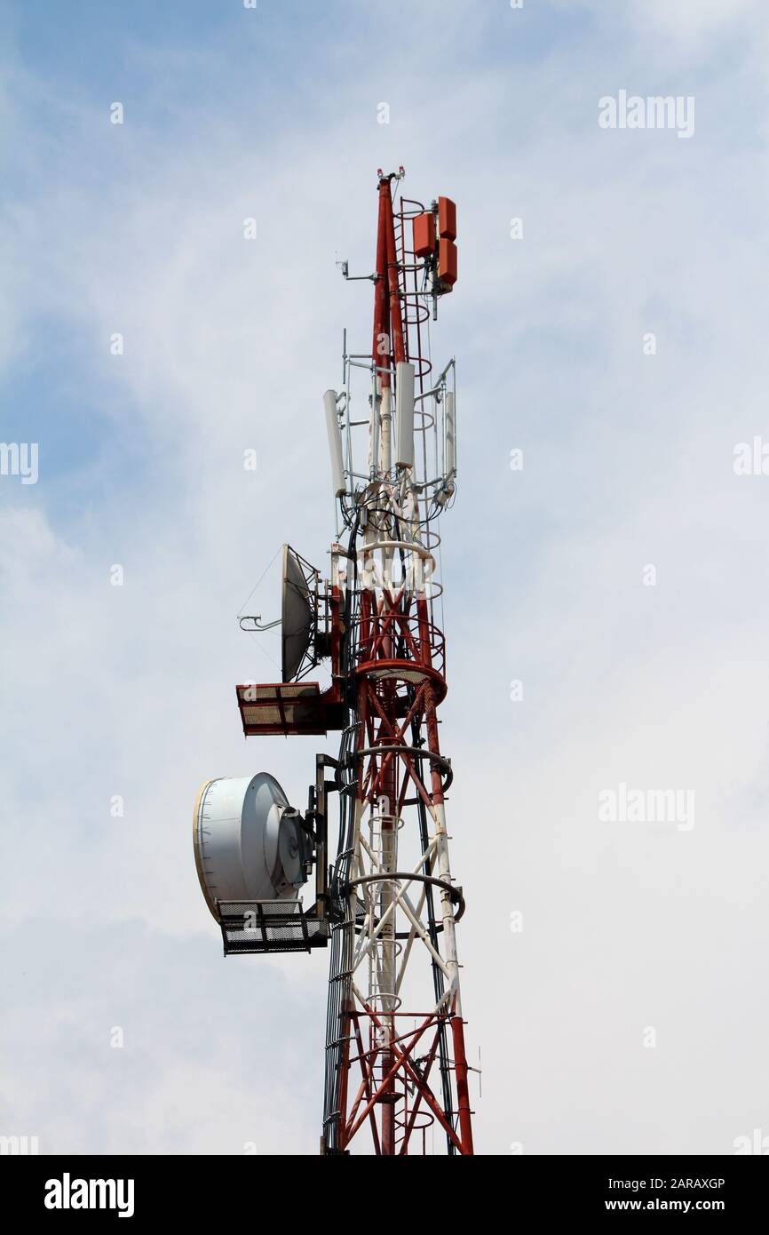 Top of strong tall cell phone red and white antenna tower with multiple antennas and ...