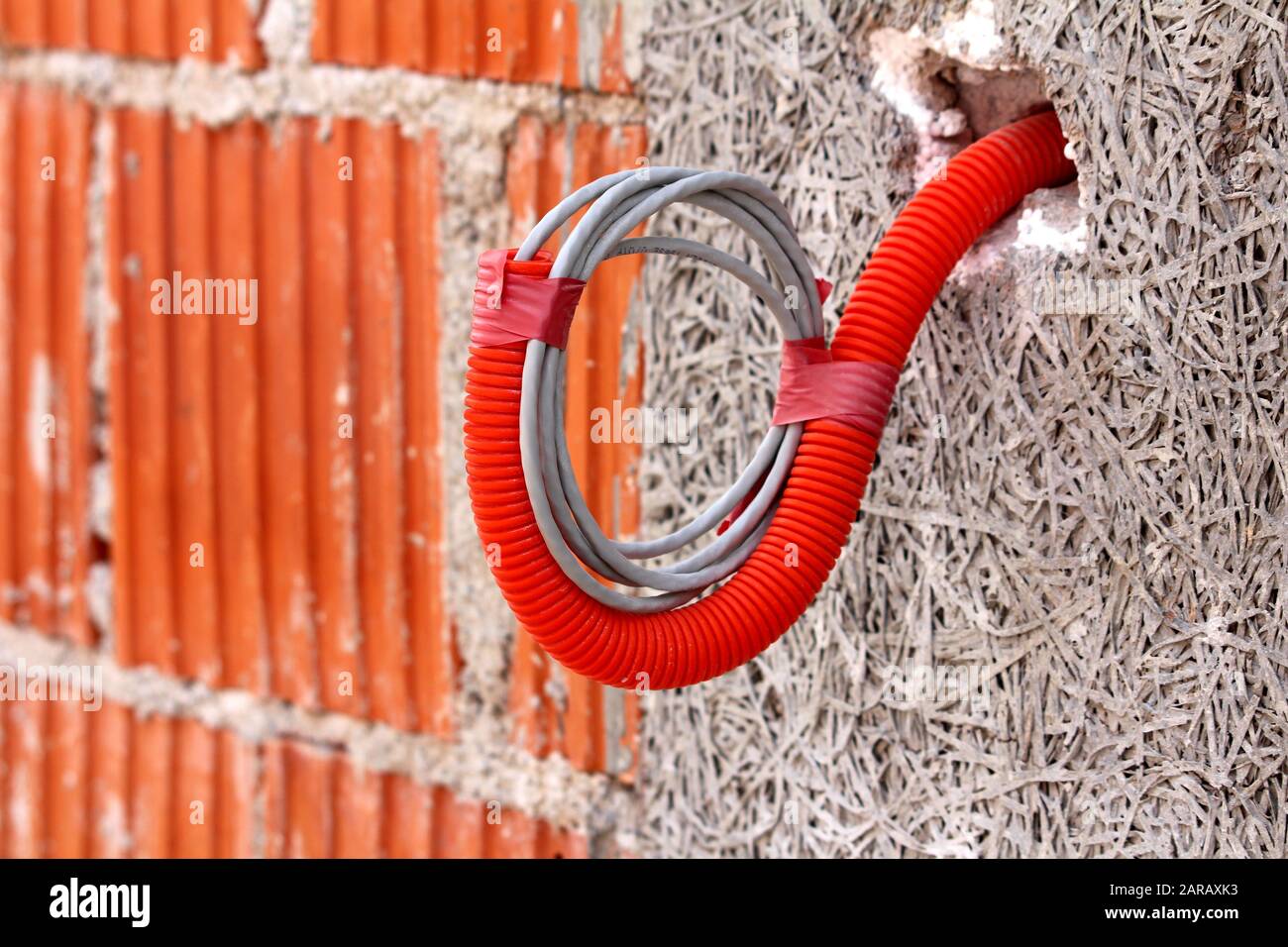 Twisted electrical wire wrapped in grey rubber insulation within red ...