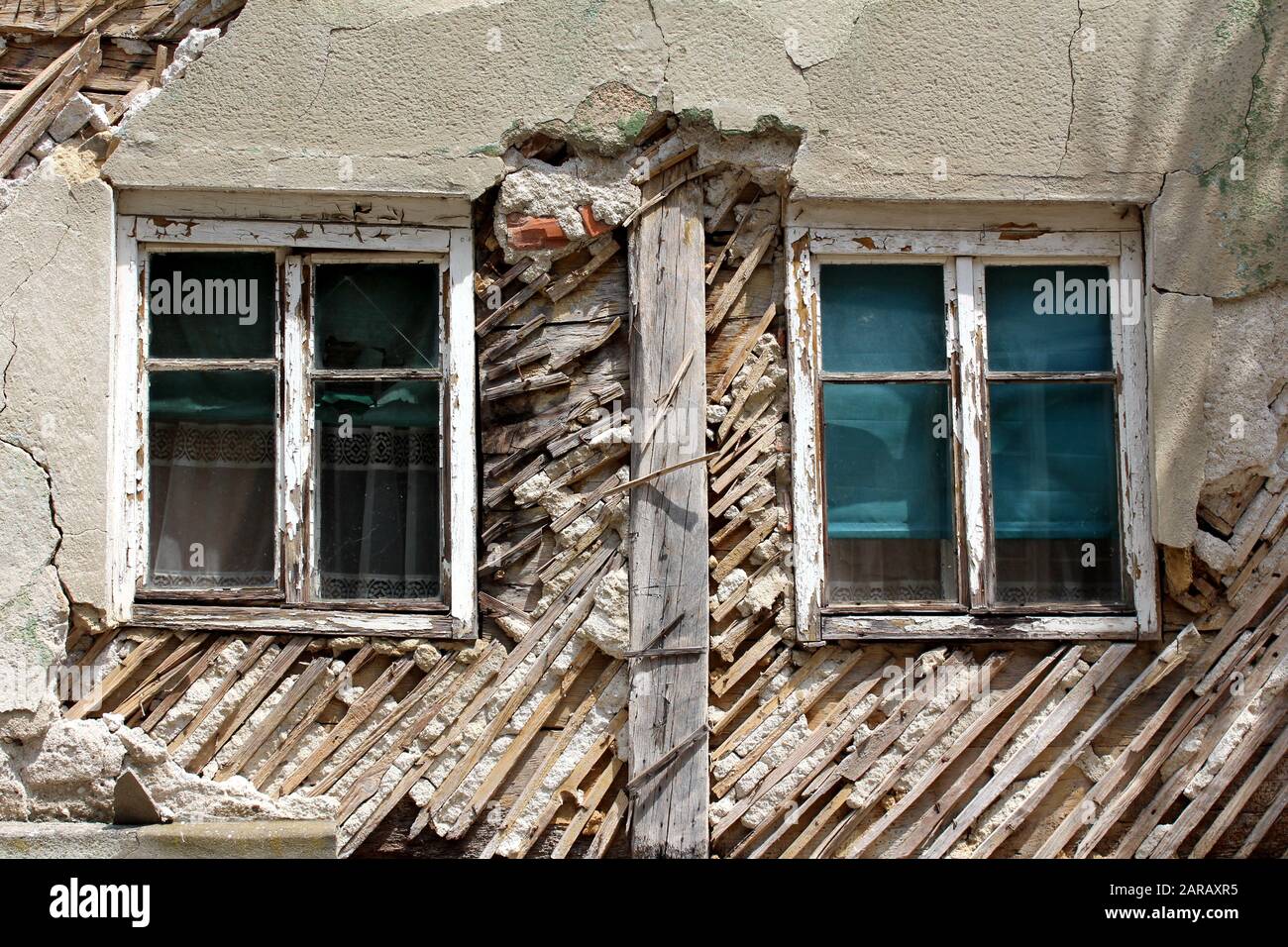 Two old windows with cracked white wooden frames on abandoned suburban family house ruins with ...