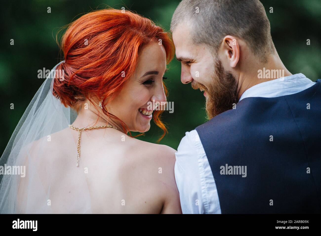 Happy newly wed couple sitting with their faces turned to each other ...