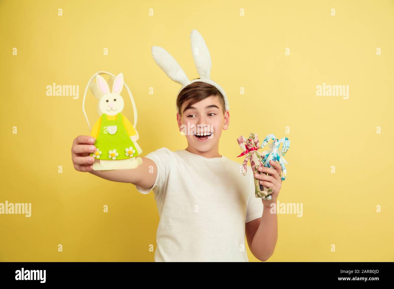 Astonished. Decorating. Caucasian boy as an Easter bunny on yellow ...