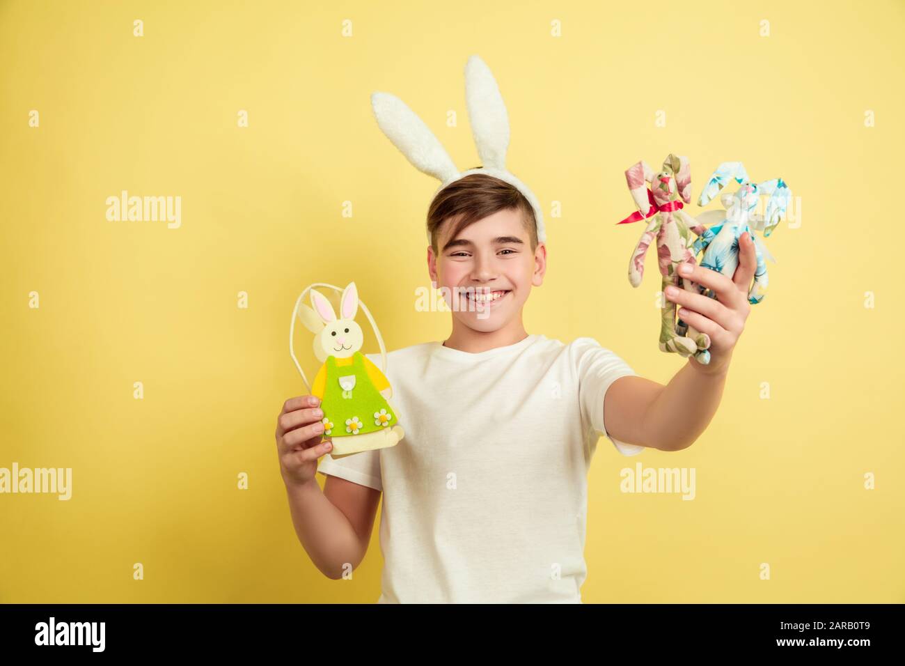 Delighted. Decorating. Caucasian boy as an Easter bunny on yellow ...