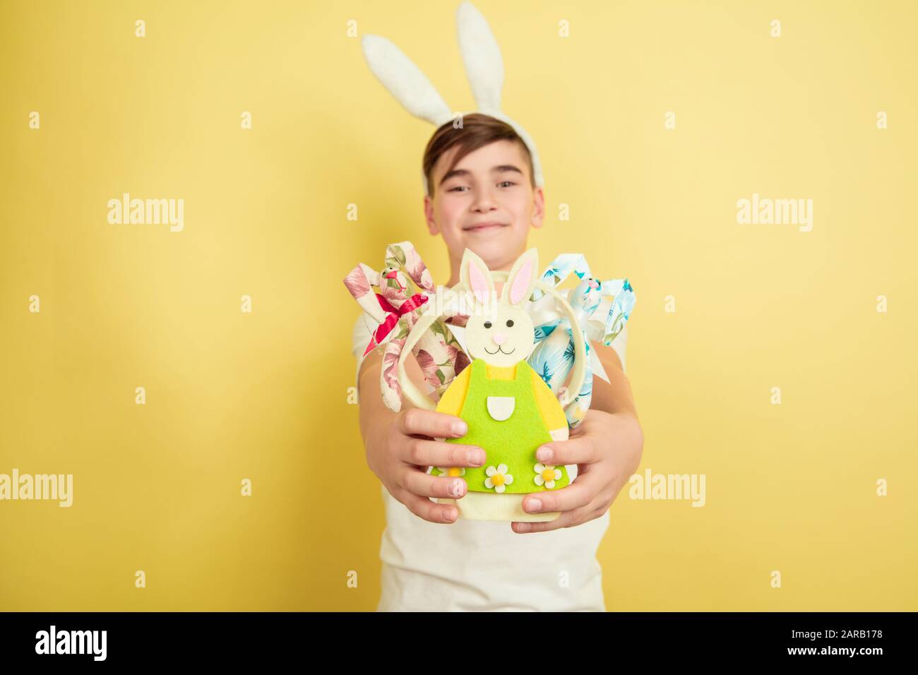 Toys giving. Decorating. Caucasian boy as an Easter bunny on yellow ...