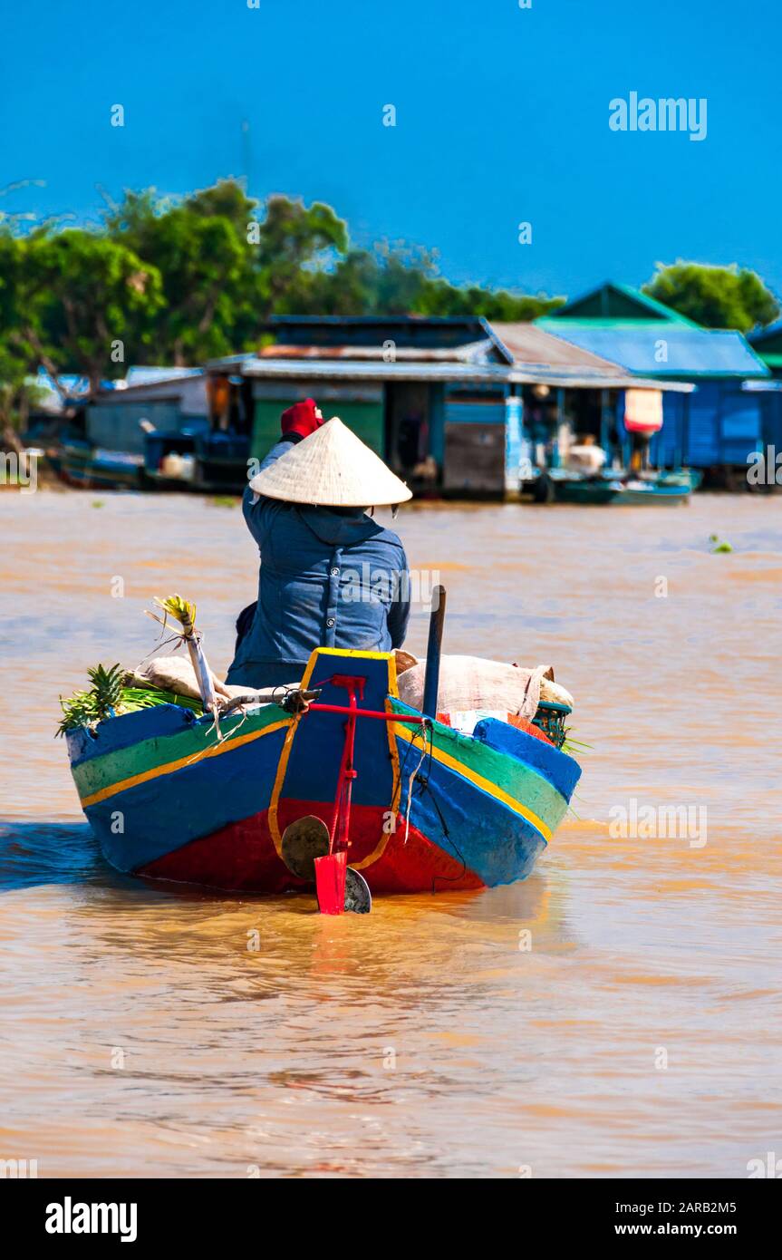A woman rows a colorful blue, red, green and yellow boat with a ...