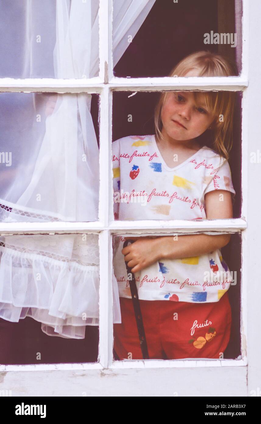 young girl stuck indoors looking out of a window looking sad Stock ...