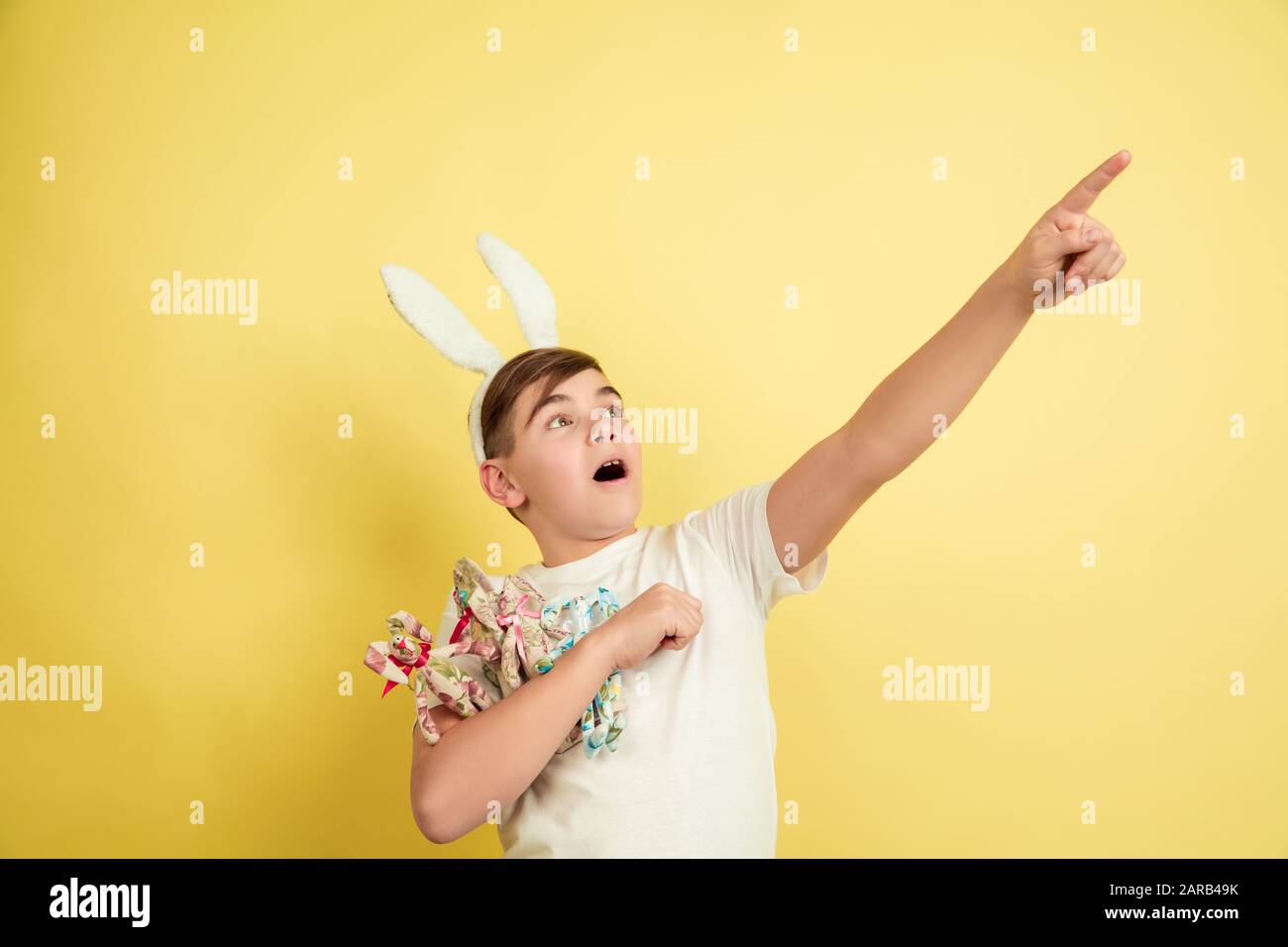 Astonished pointing up. Decorating. Caucasian boy as an Easter bunny on ...