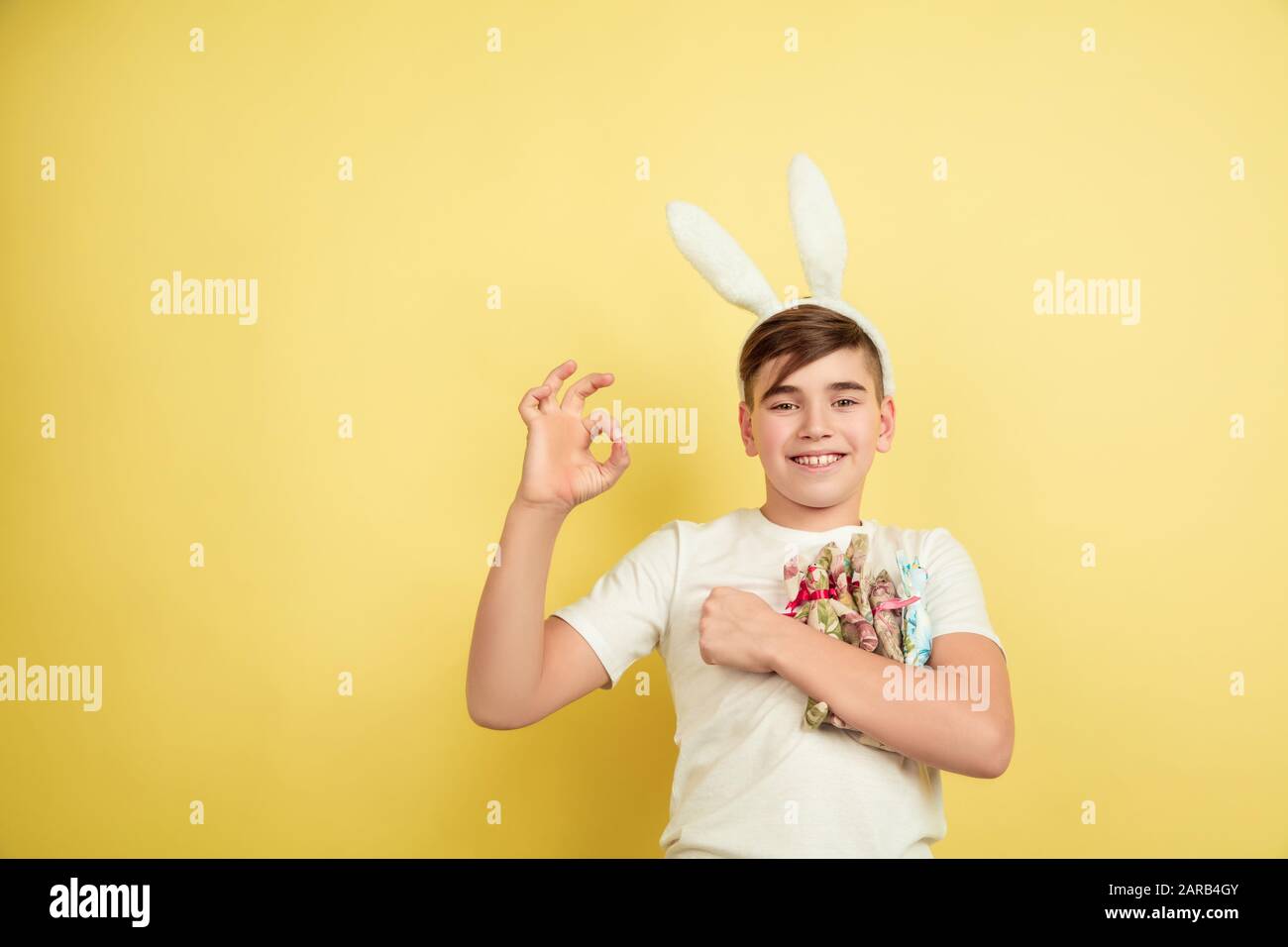 Showing nice. Decorating. Caucasian boy as an Easter bunny on yellow ...