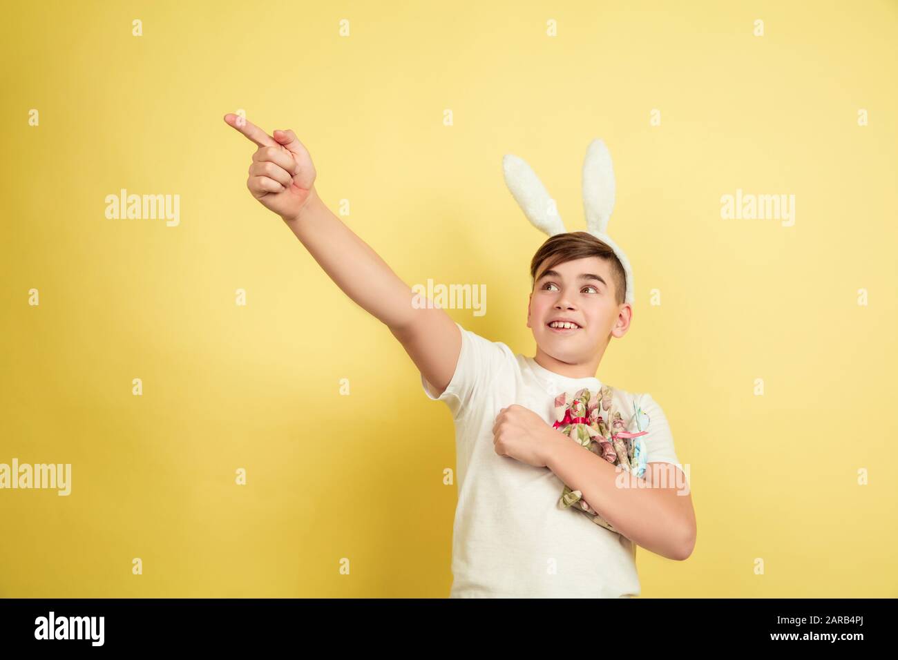 Astonished pointing up. Decorating. Caucasian boy as an Easter bunny on ...