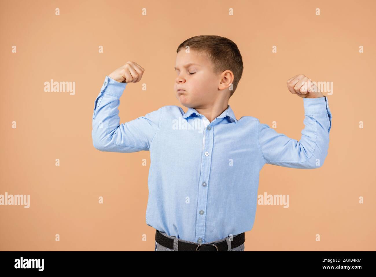 little boy shows his biceps on beige background. child showing his ...