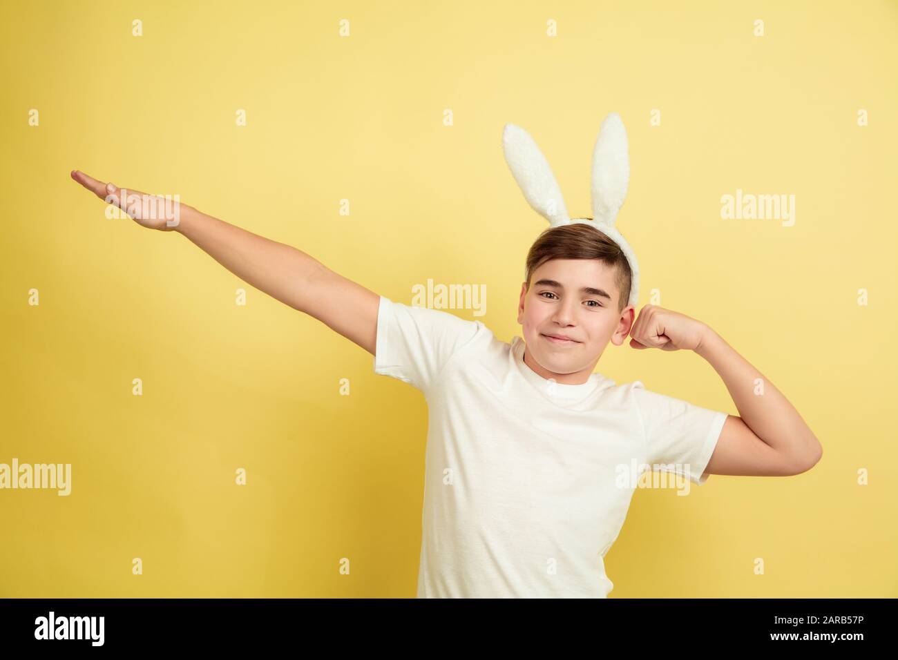 Successful winner gesture. Caucasian boy as an Easter bunny on yellow ...