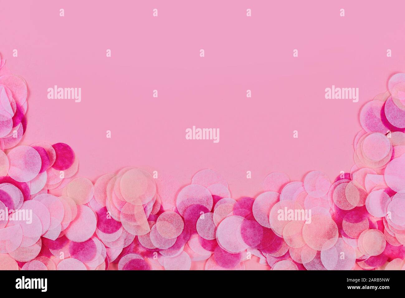 Pink party background with multicoloredpaper confetti at bottom border ...