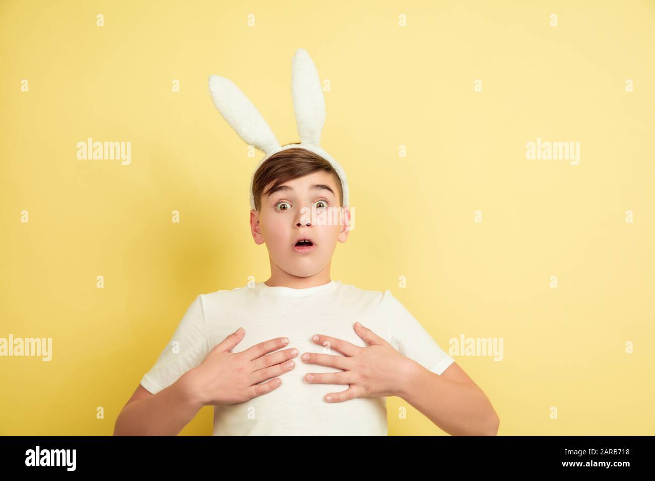 Shocked, astonished. Caucasian boy as an Easter bunny on yellow studio ...
