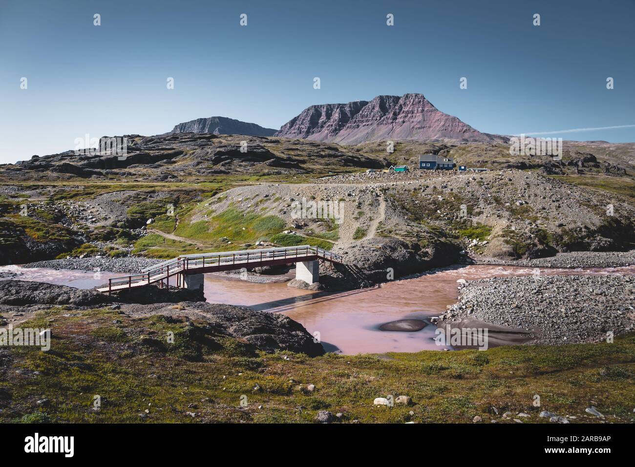 Hiking path on arctic Disko island in Greenland. River bed with bridge ...