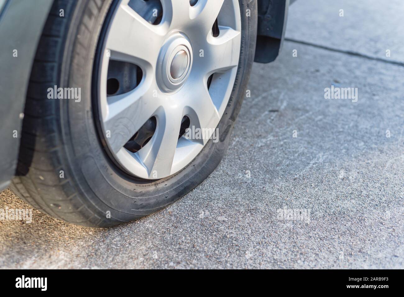 Flat rear tire on green car on driveway of parking garage close-up ...