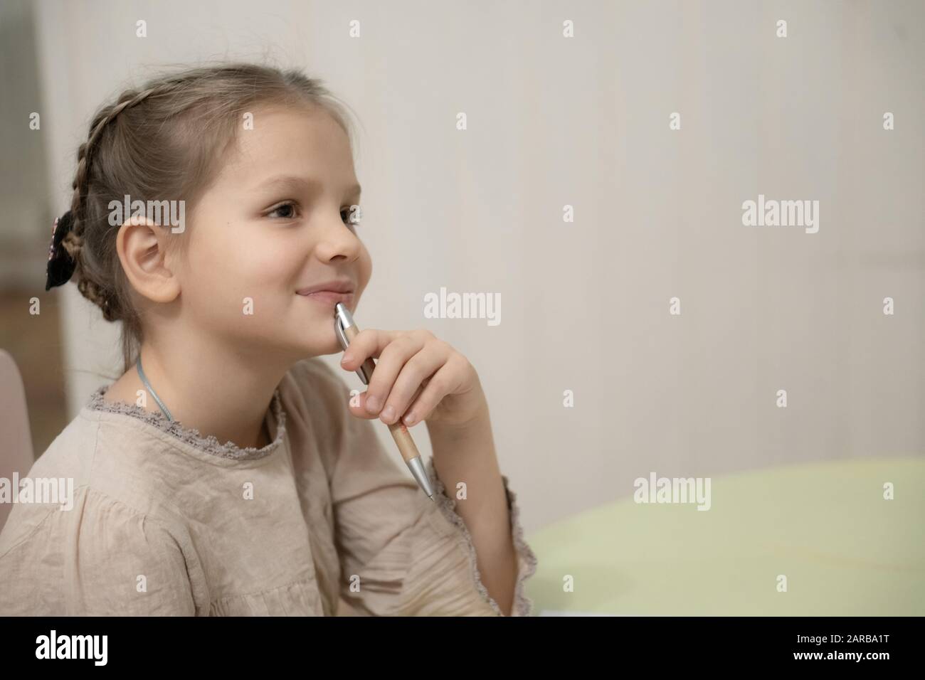 A dark blond girl in a beige dress is doing homework Stock Photo - Alamy