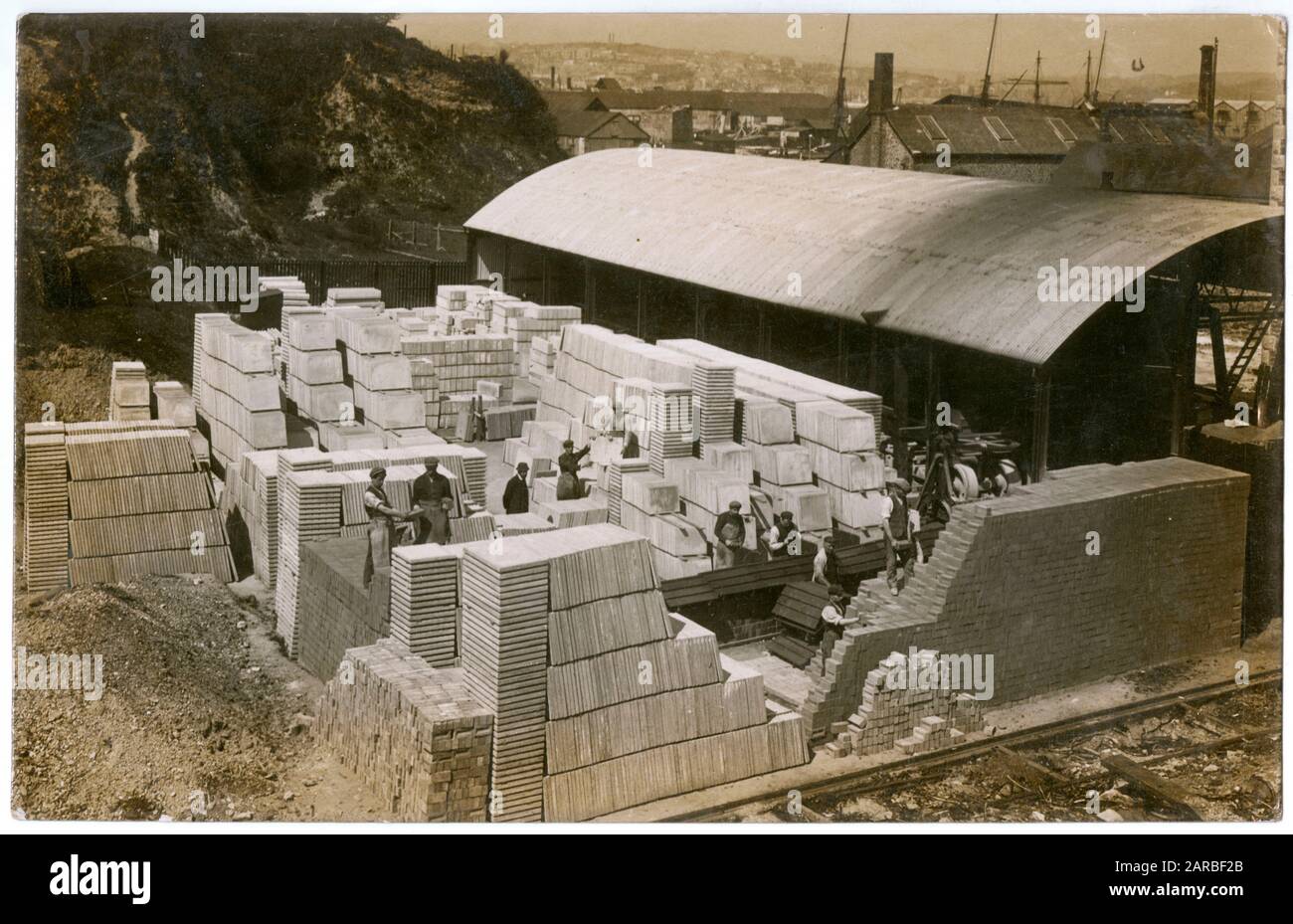 Men at work in a storage area, surrounded by piles of paving stones and ...