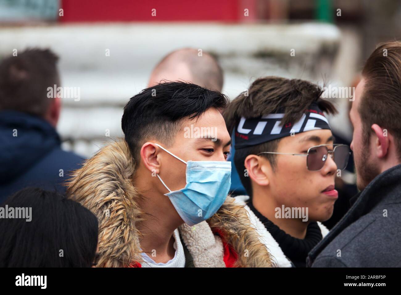 A man of Asian appearance wearing a face mask whilst out in a crowd ...