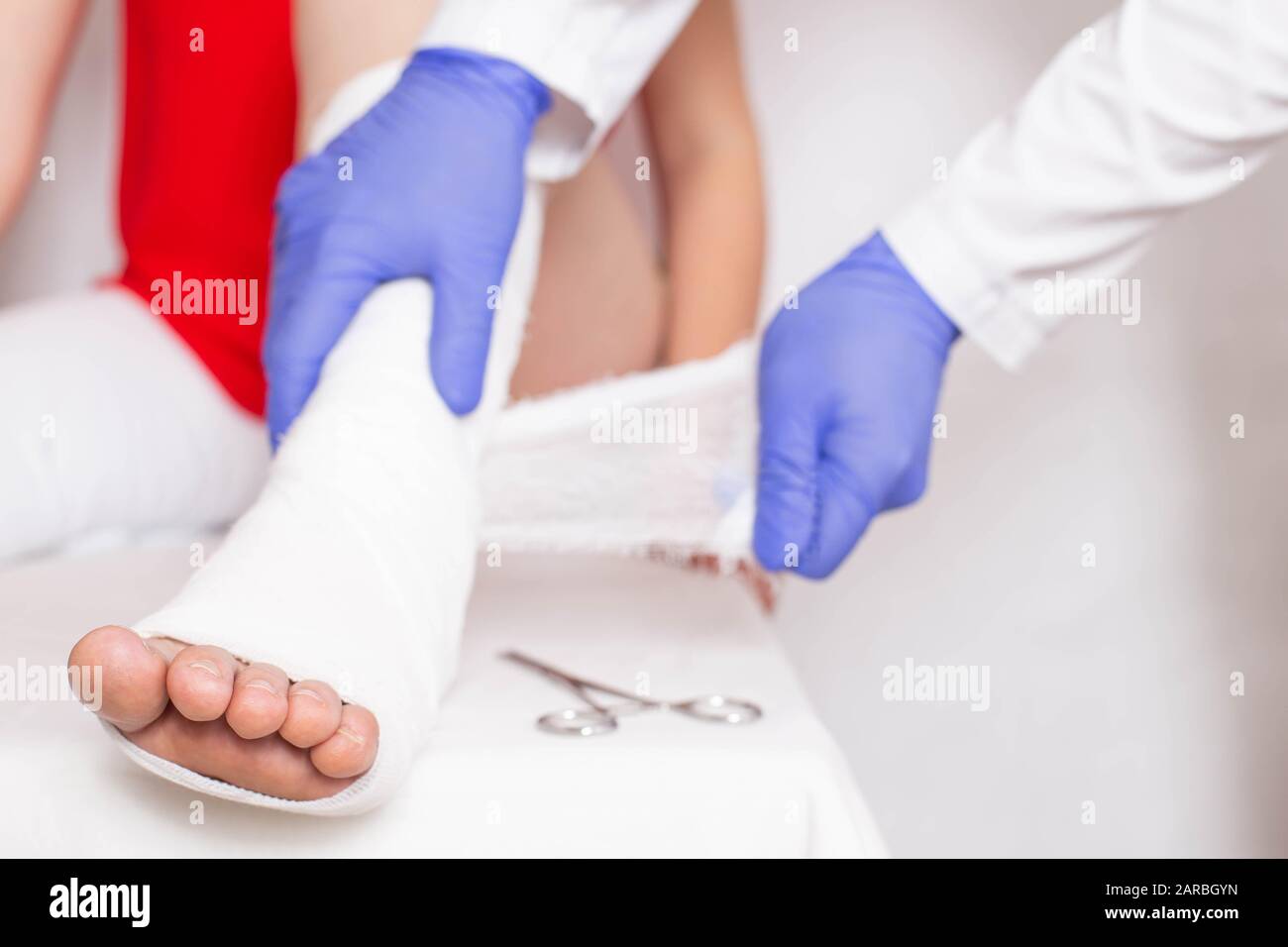 Doctor traumatologist establishes a fixing bandage to a girl athlete on ...