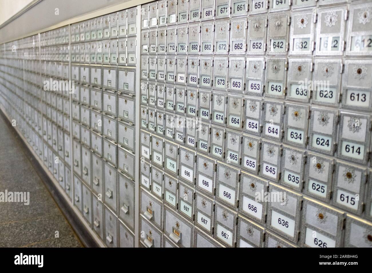 Long wall of grey post office locker boxes of different sizes in ...