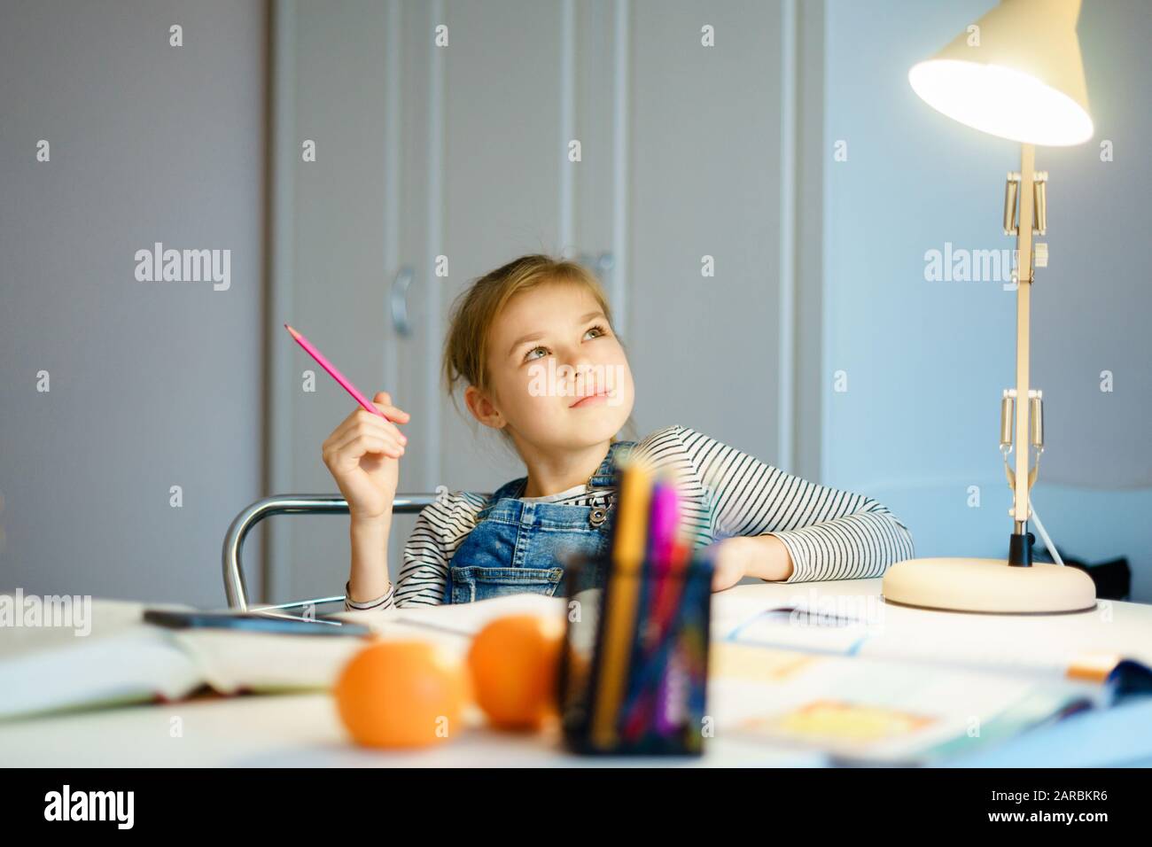 Kid thinking wile doing her homework Stock Photo - Alamy