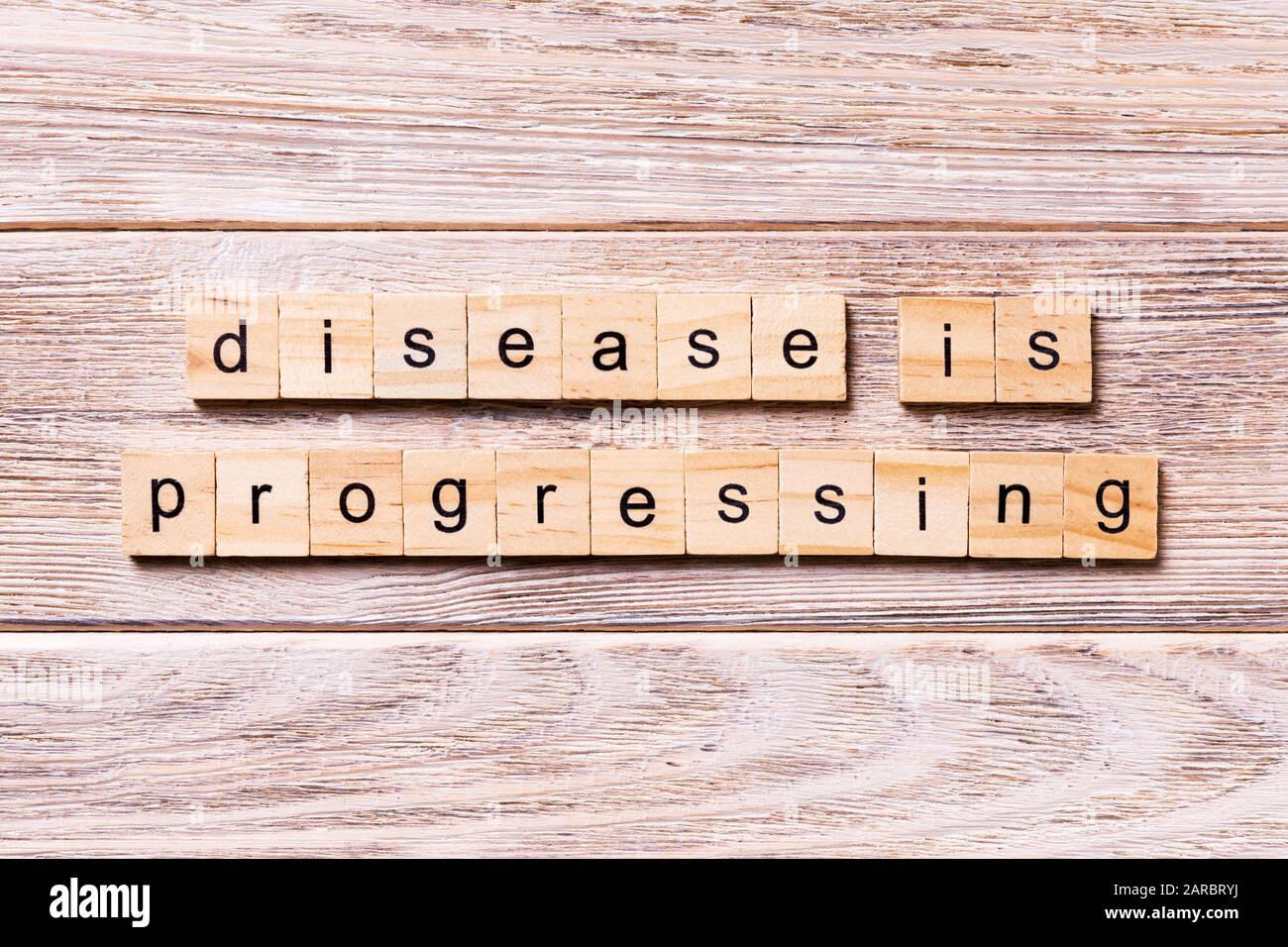 disease is progressing word written on wood block. disease is ...