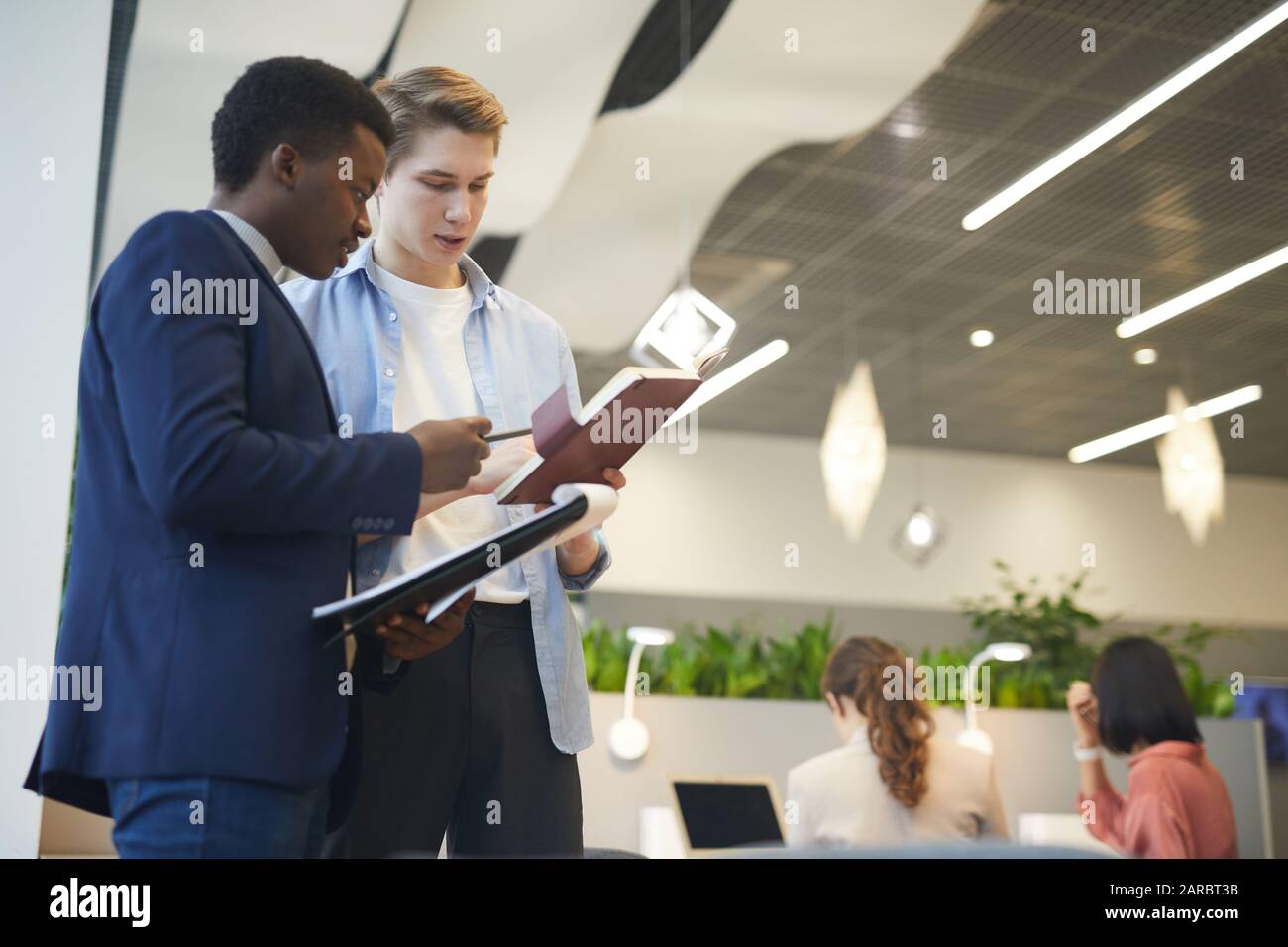 Low angle portrait of two young businessmen discussing work project ...