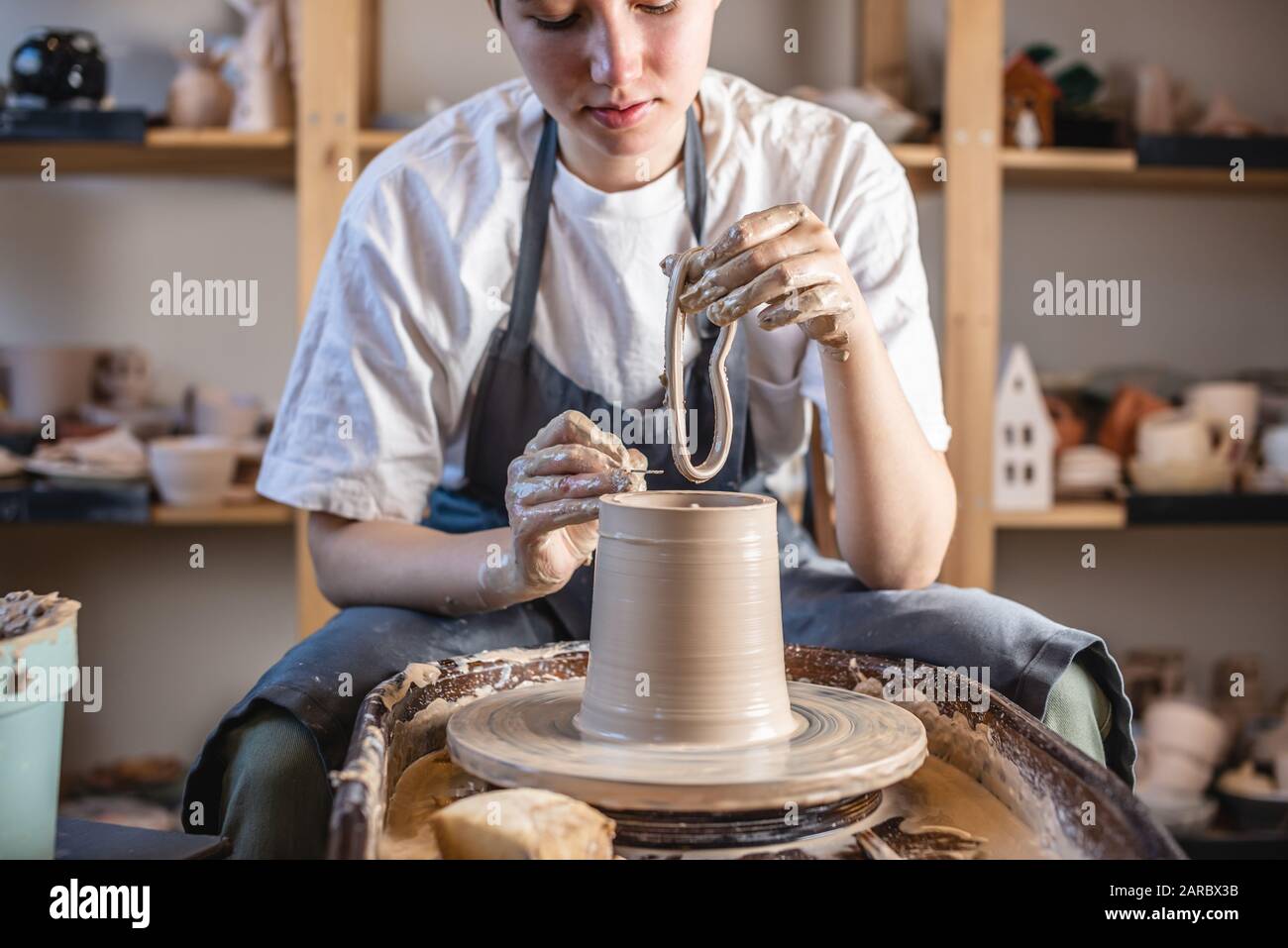 Potter working on a Potter's wheel making a vase. Young woman forming ...
