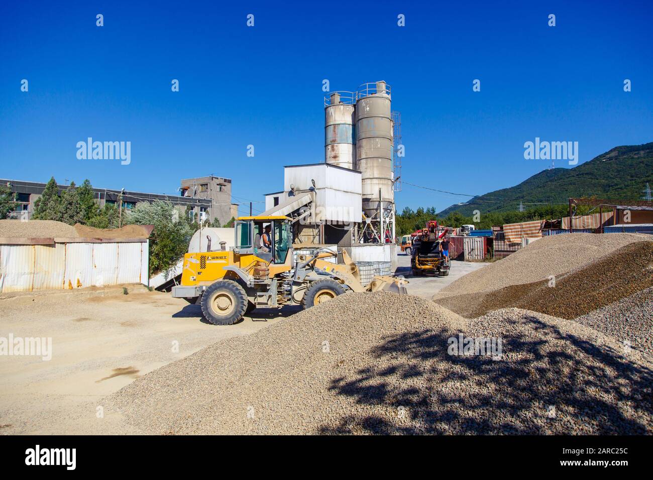 Tractor-loader loads rubble on a bright Sunny day. Piles of rubble. In ...
