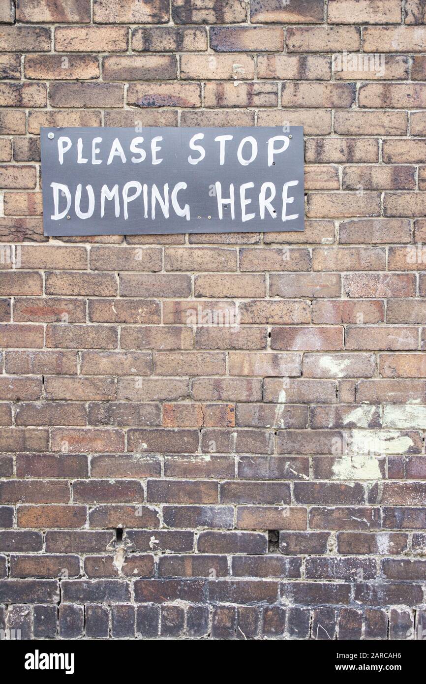 Vertical shot of a Please stop dumping here sign on a brick wall Stock ...
