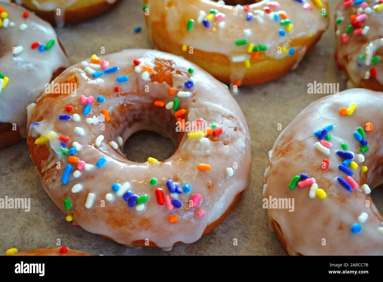 Fresh donuts with white icing and colorful sprinkles Stock Photo - Alamy