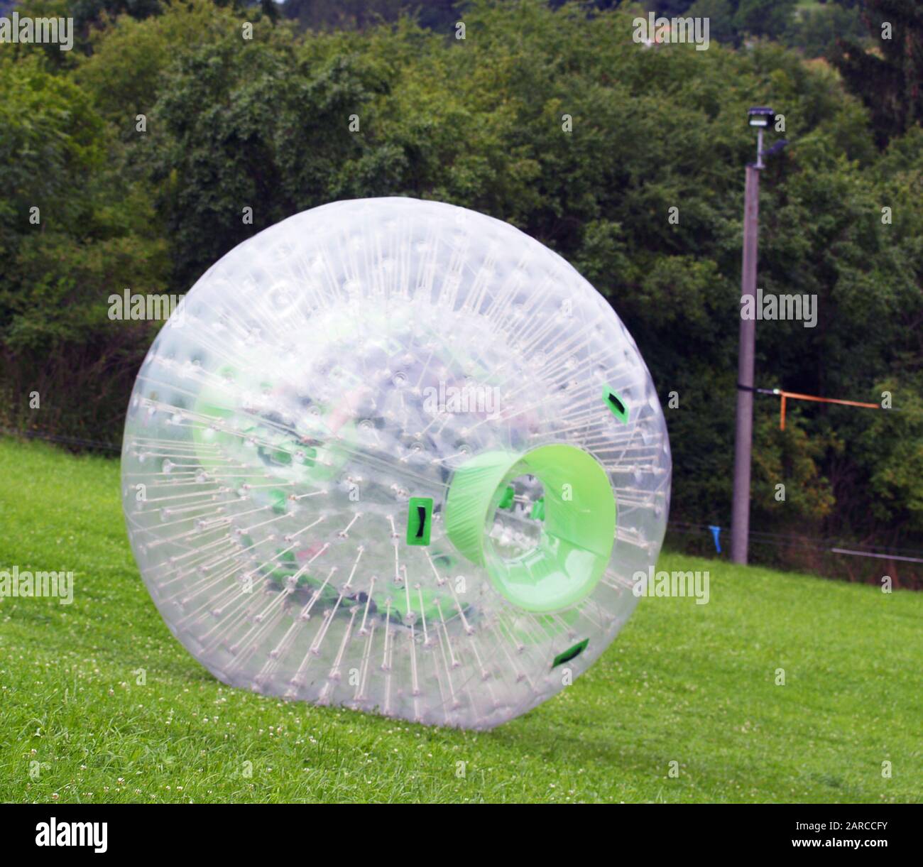 Zorb ball rolling down the medow Stock Photo - Alamy
