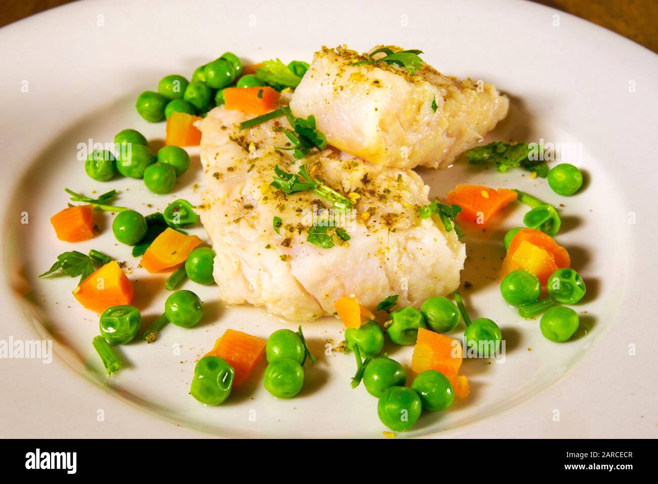 Italian food: close-up of a dish of filleted fish with carrots and peas ...