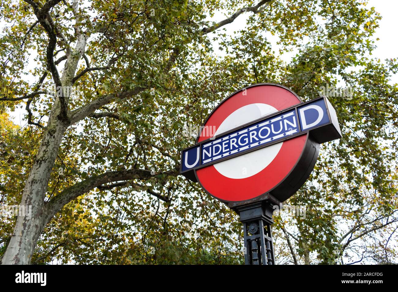 Low angle shot of the underground sign surrounded by trees Stock Photo ...
