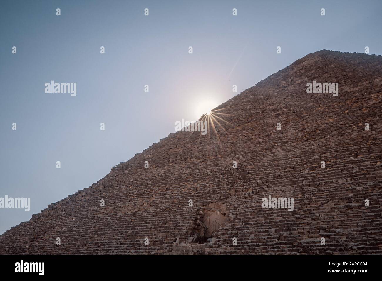 Low angle shot of the sun shining from behind the Great Pyramid of Giza ...