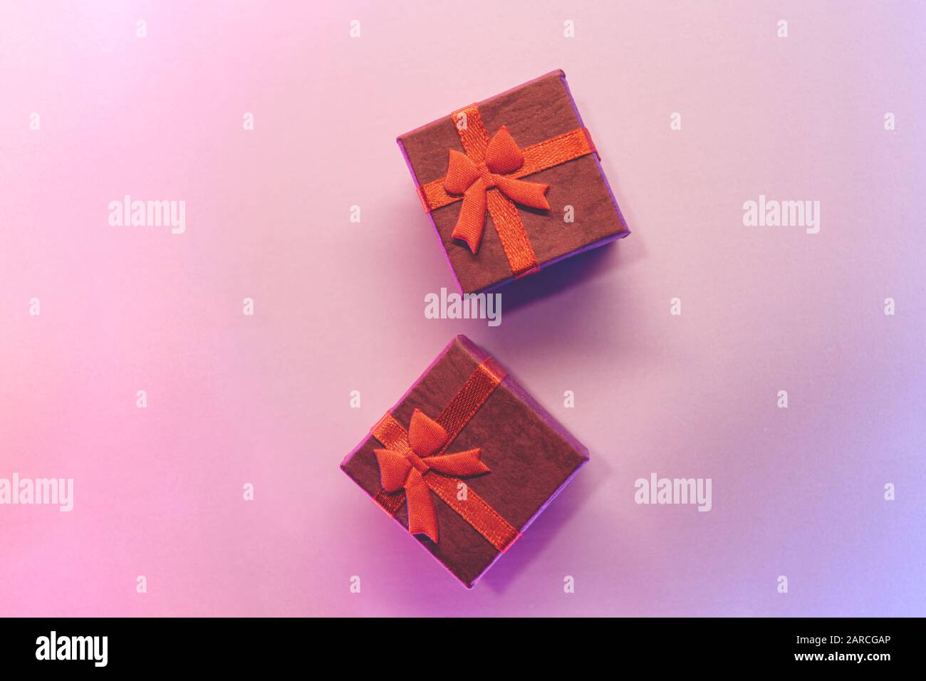Two red gift boxes on a gradient background lit by neon lights. Holiday ...