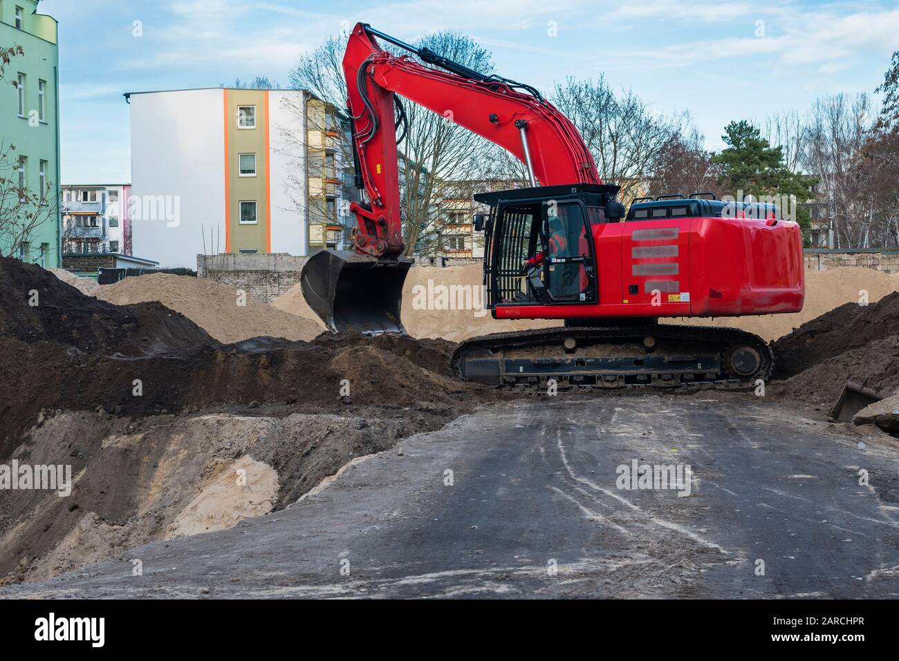 An excavator prepares the foundation of a new building, housing ...