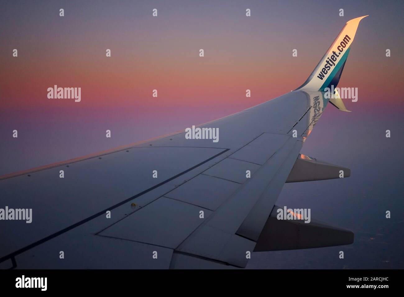 West Jet aircraft wing at sunset in mid air Stock Photo - Alamy