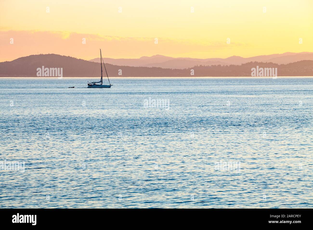 A sailboat motoring through the Haro Strait between San Juan Island and ...