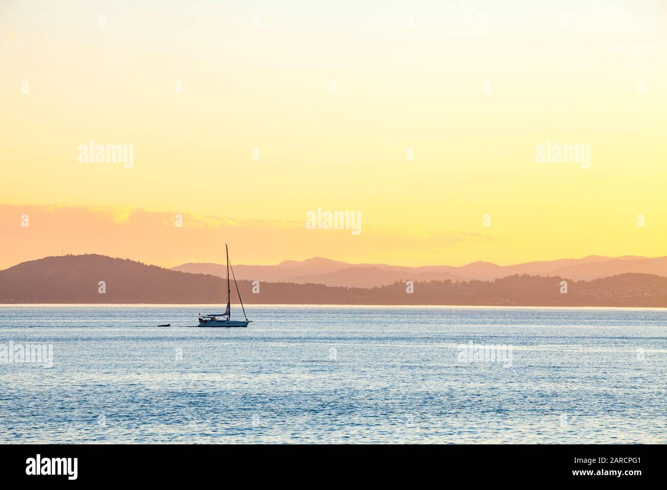 A sailboat motoring through the Haro Strait between San Juan Island and ...