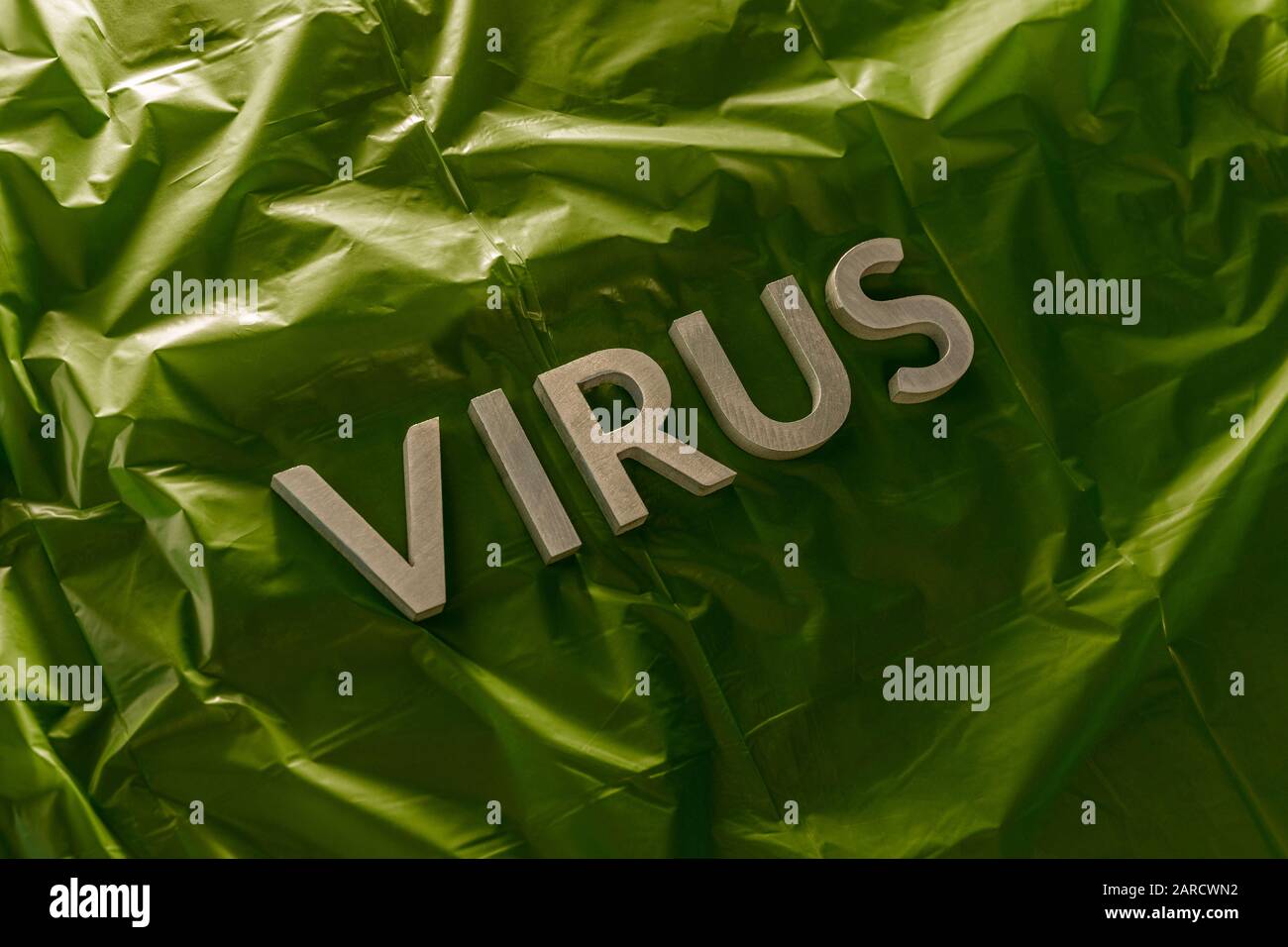 the word virus laid with silver metal letters on crumpled green plastic ...