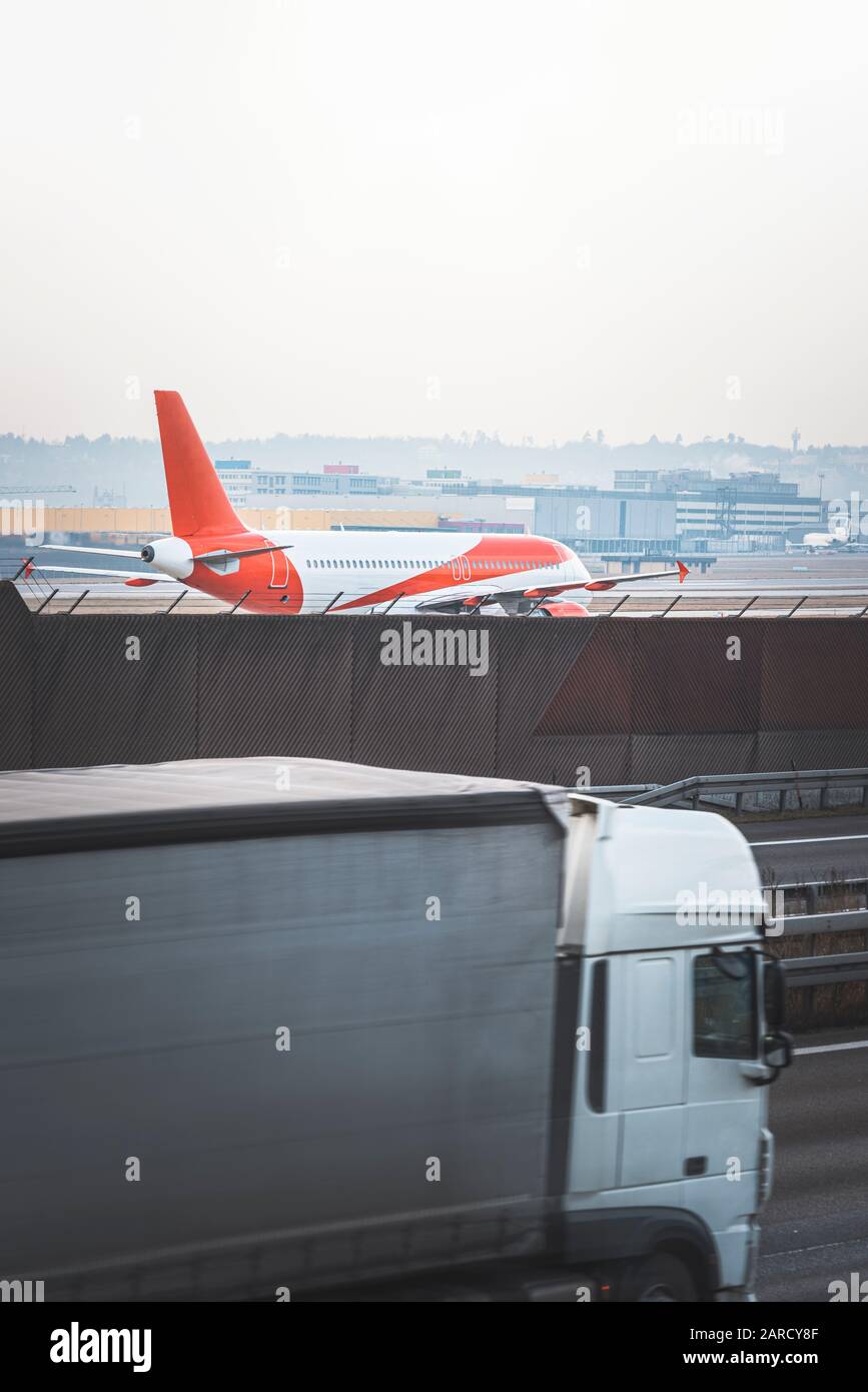 Passengers plane and cargo truck moving side by side. White and red ...