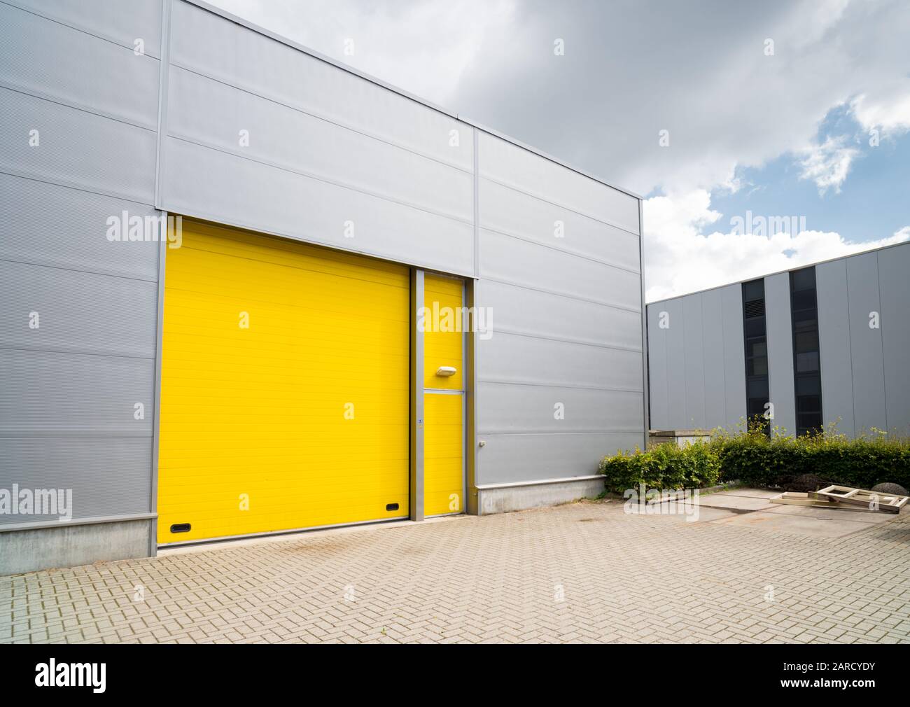 commercial warehouse exterior with a yellow roller door Stock Photo - Alamy