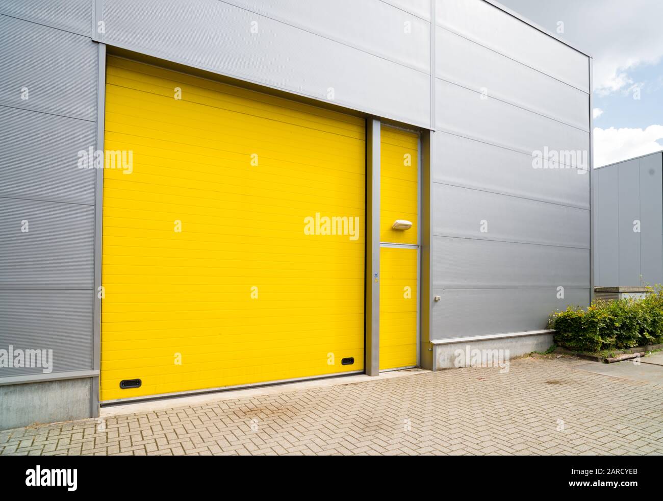 commercial warehouse exterior with a yellow roller door Stock Photo - Alamy