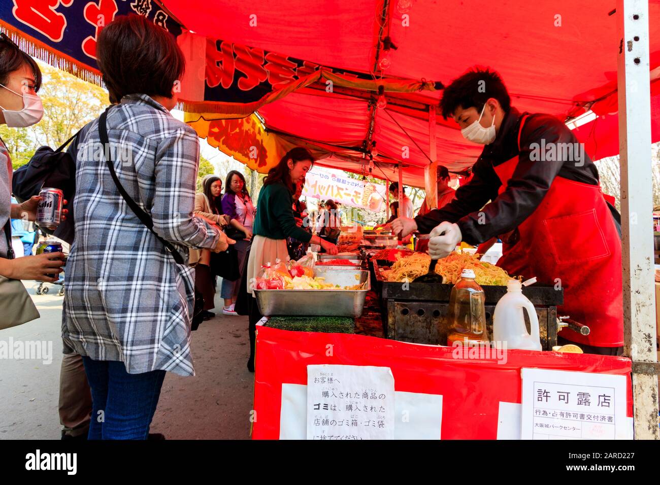View along of people buying plastic boxes of noodles at food stall with ...